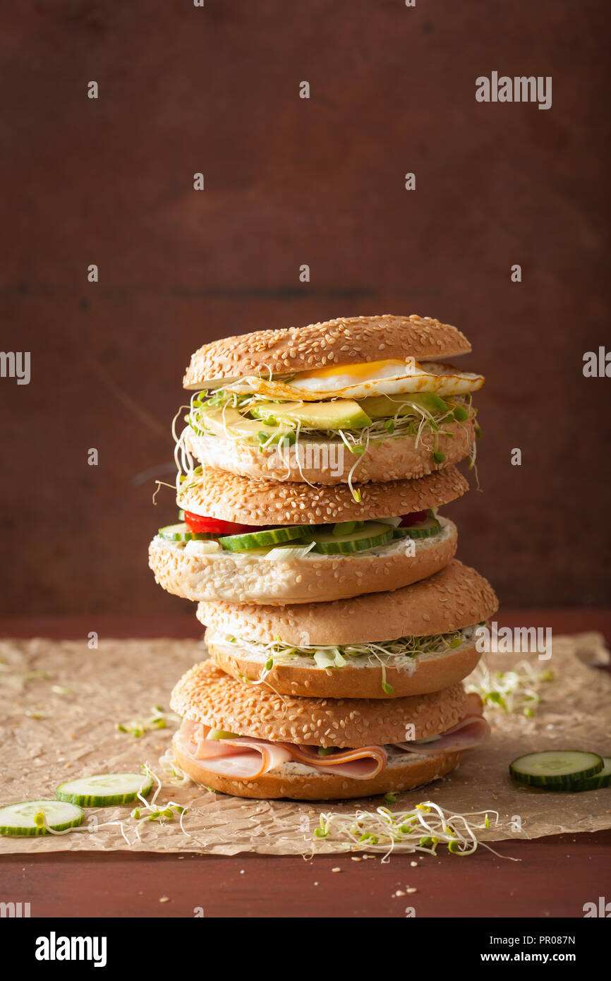 variety of sandwiches on bagels: egg, avocado, ham, tomato, soft cheese ...