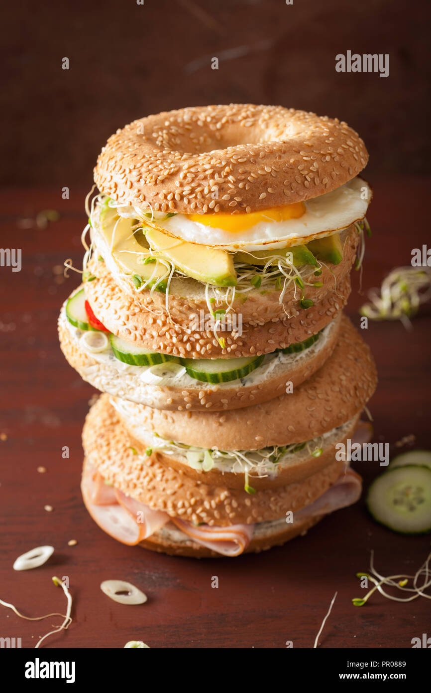 variety of sandwiches on bagels: egg, avocado, ham, tomato, soft cheese ...