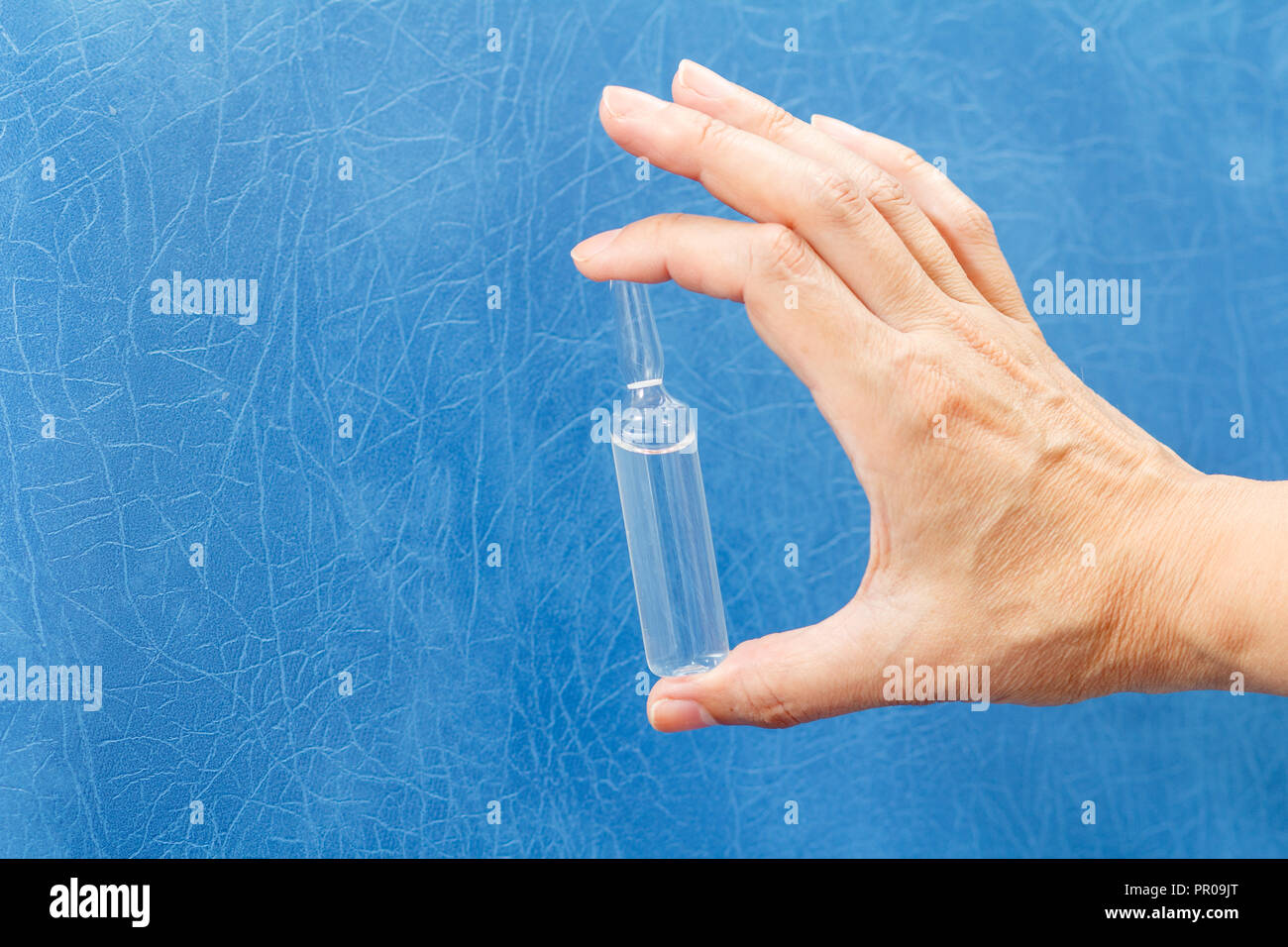 Hand of female with ampoule and medicine on blue background. Selective ...