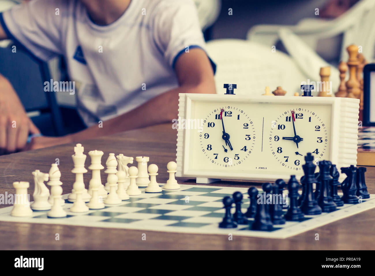 Chess board with chess pieces and clock on wooden desk The chess ...