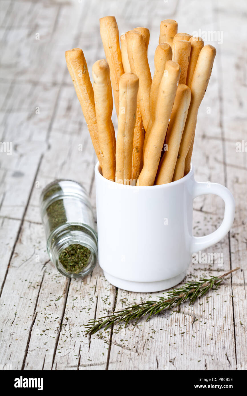 cup with bread sticks grissini and rosemary on rustic wooden background ...