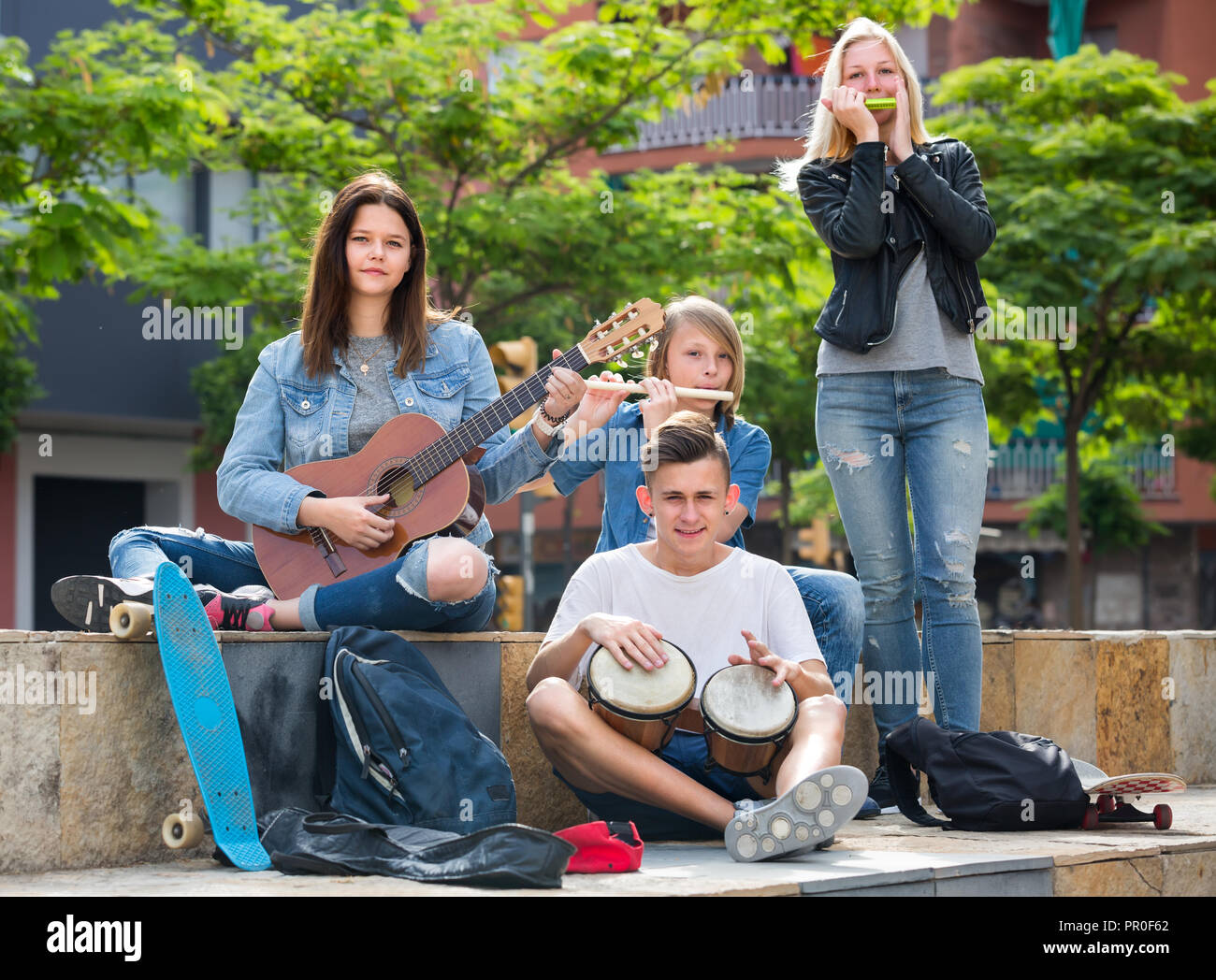 Portrait of four smiling teenage musicians playing music together ...