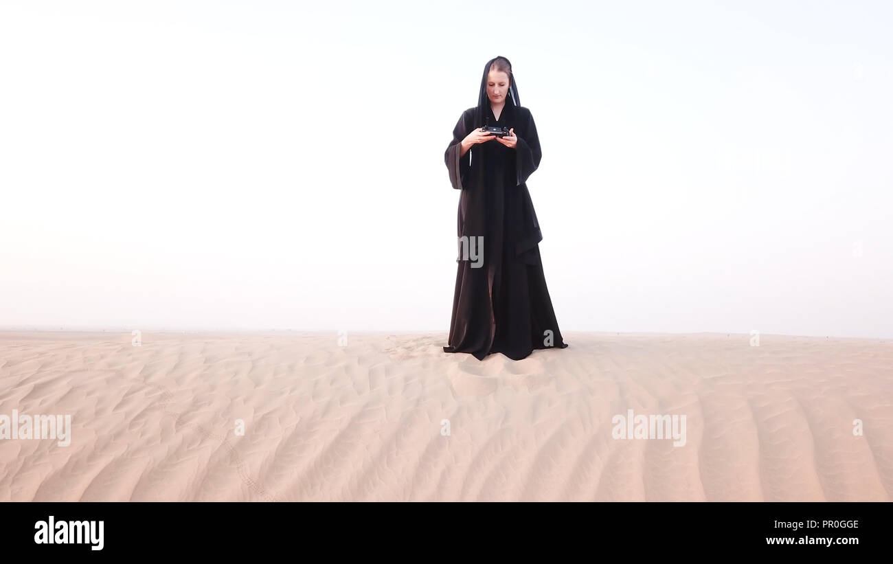 A woman in abaya (United Arab Emirates traditional dress) flying a ...