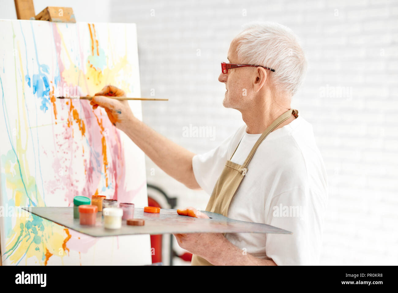 Side view of senior talented painter while painting his masterpiece at ...
