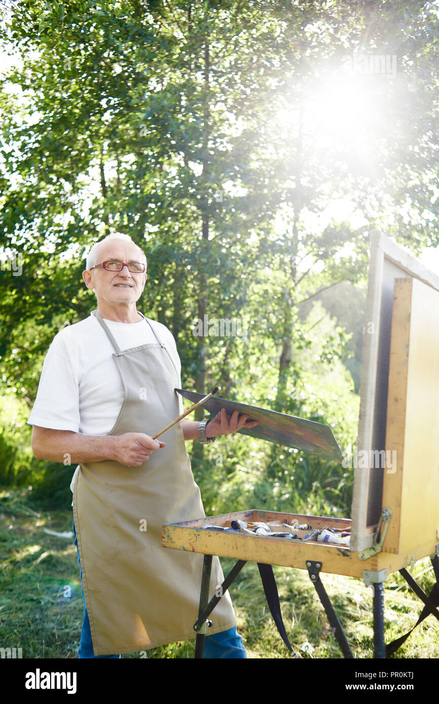 Handsome male artist, with conceived look, holding brush and imagining ...