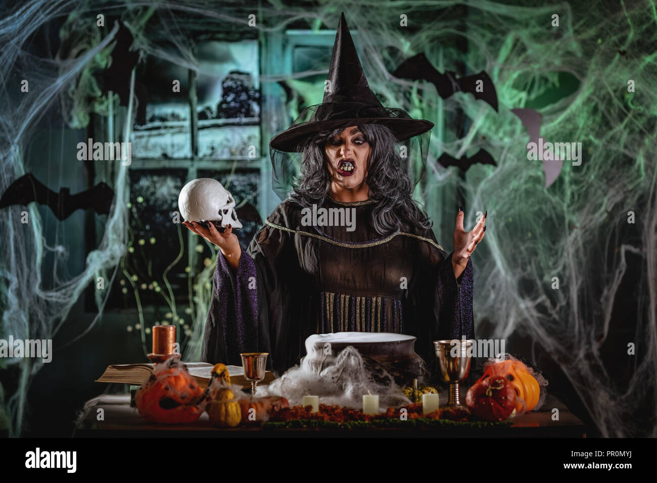 Witch with awfully face in creepy surroundings full of cobweb with ...