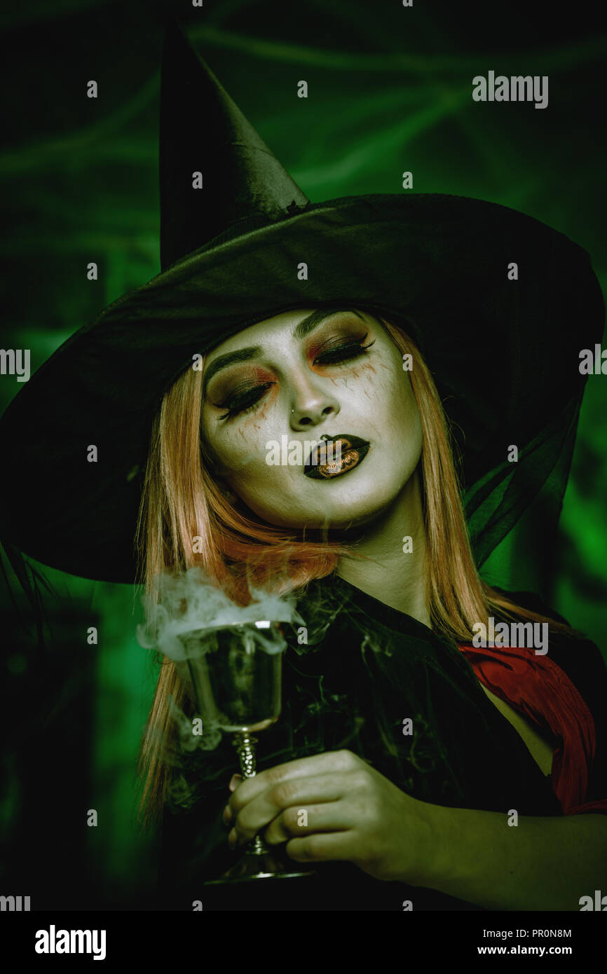 Witch with awfully face in creepy surroundings and smoky green ...