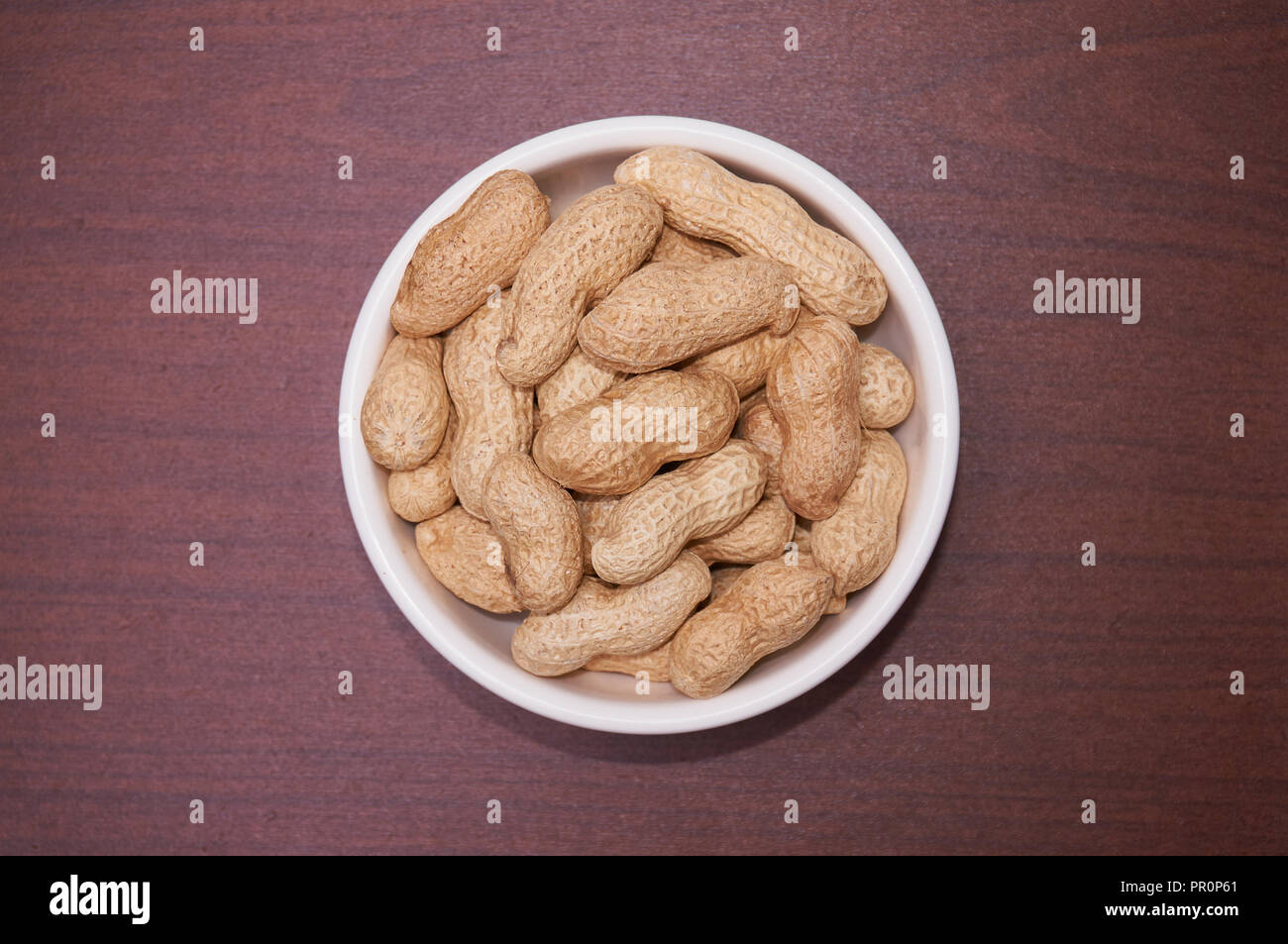 Peanuts uncleaned against a background of brown wood Stock Photo - Alamy