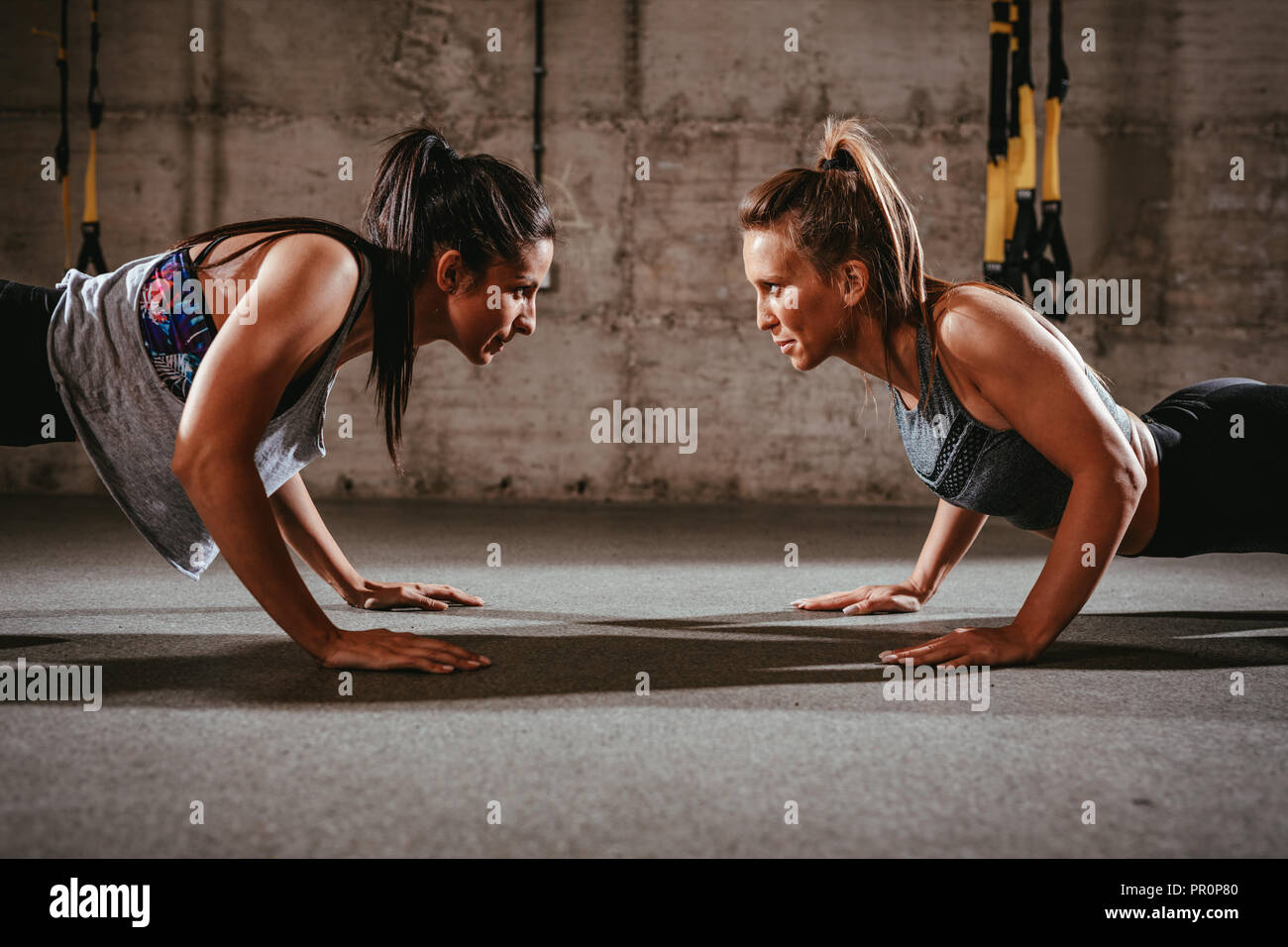 Two young muscular girls doing plank exercise at the cross fit workout ...
