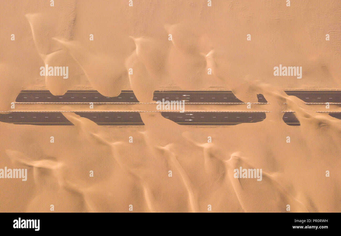 Aerial view of a desert road being run over by sand dunes photographed ...