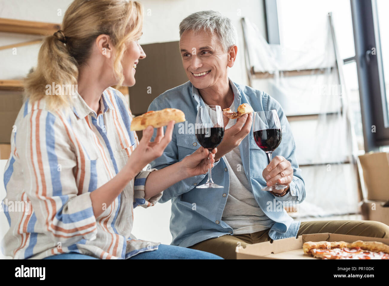 happy elderly couple eating pizza and drinking wine in new house Stock ...