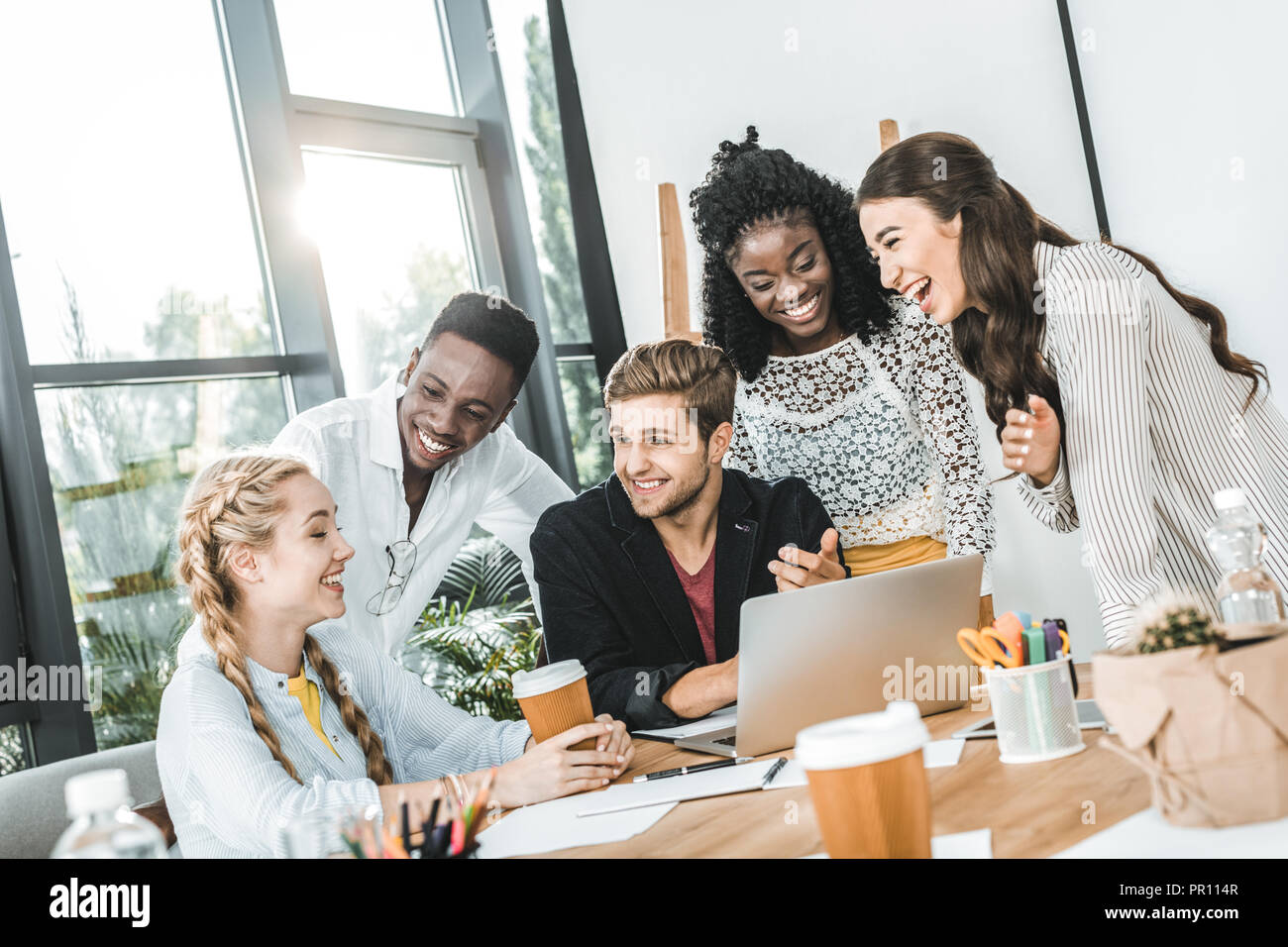 Laughing multiethnic colleagues working in hi-res stock photography and ...