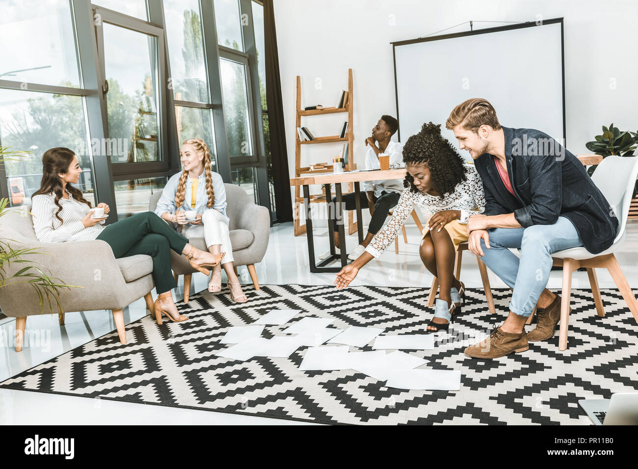 multicultural business people looking at papers on floor together in ...