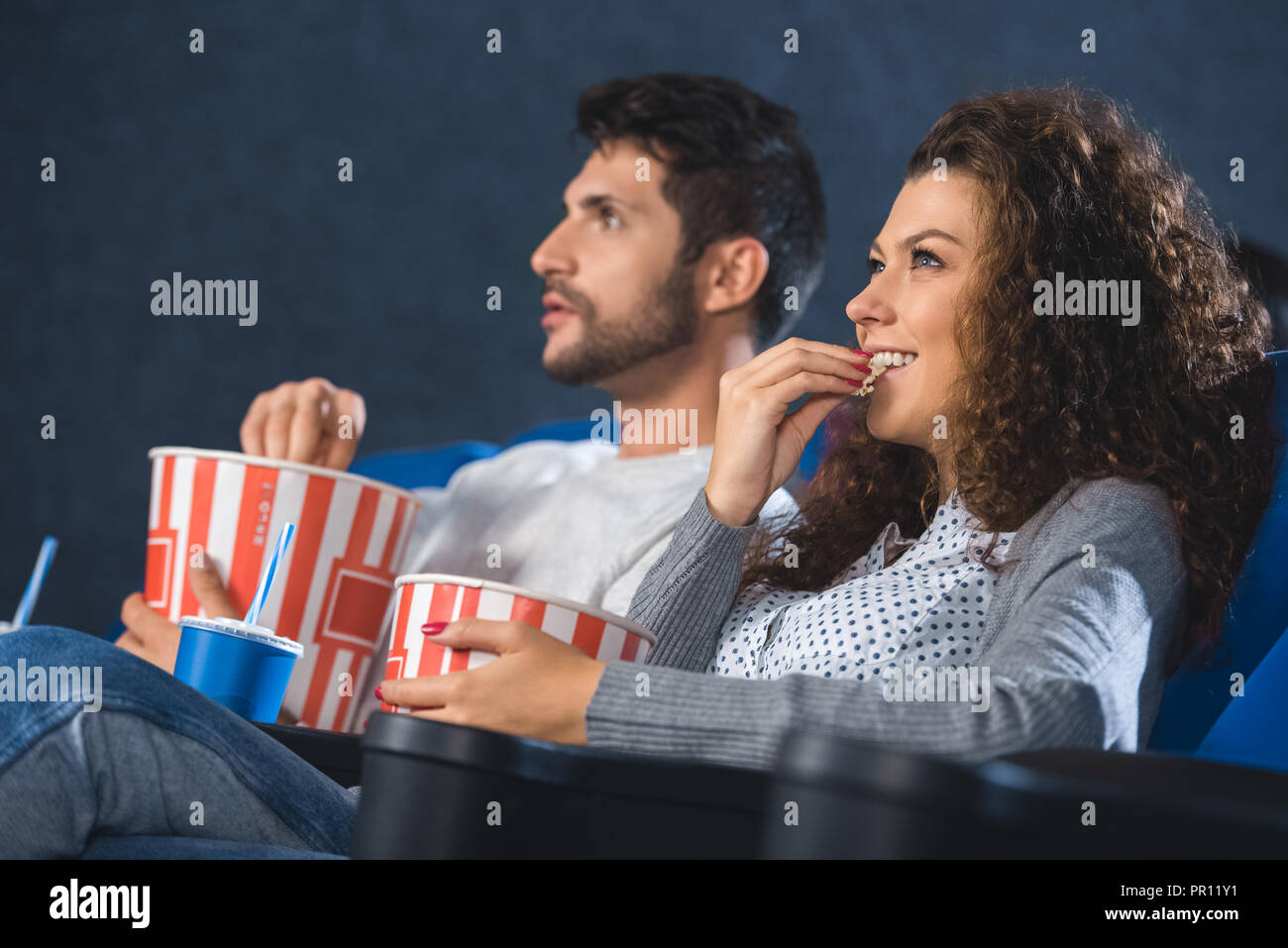Couple Eating Popcorn While Watching Film Together In Cinema Stock
