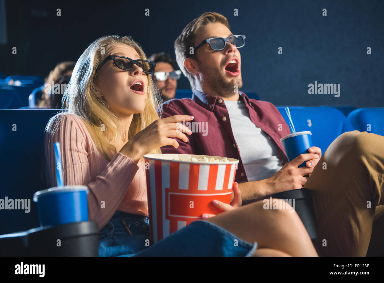 shocked couple in 3d glasses with popcorn watching film together in cinema Stock Photo - Alamy