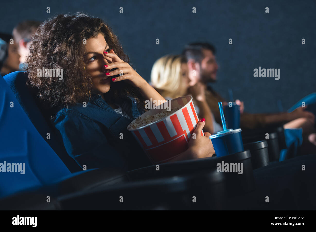 scared woman with popcorn covering eyes while watching movie in cinema ...