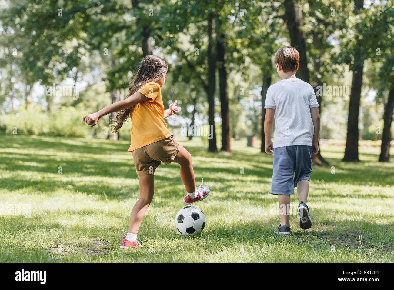 back view of children playing with soccer ball in park Stock Photo - Alamy