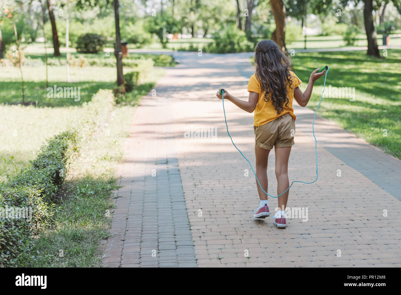 back view of cute kid walking with jumping rope in park Stock Photo - Alamy