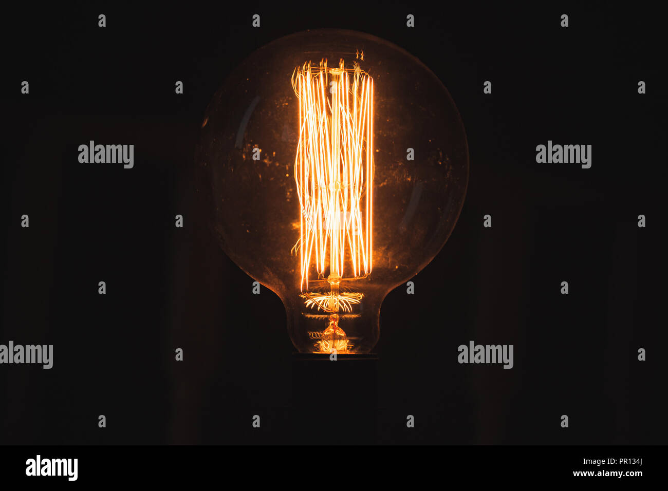 Vintage stylized tungsten lamp glowing in dark, close-up photo with ...