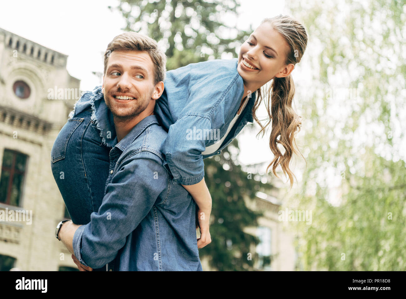 happy young man carrying his girlfriend on shoulder at park Stock Photo ...