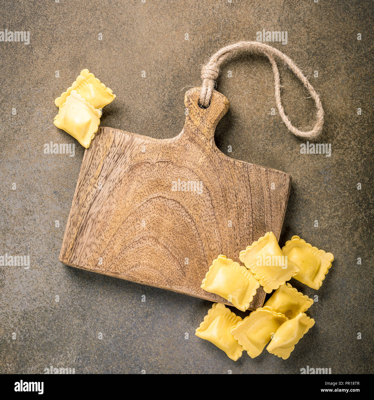 Fresh homemade italian filled square pasta ravioli on wooden cutting ...