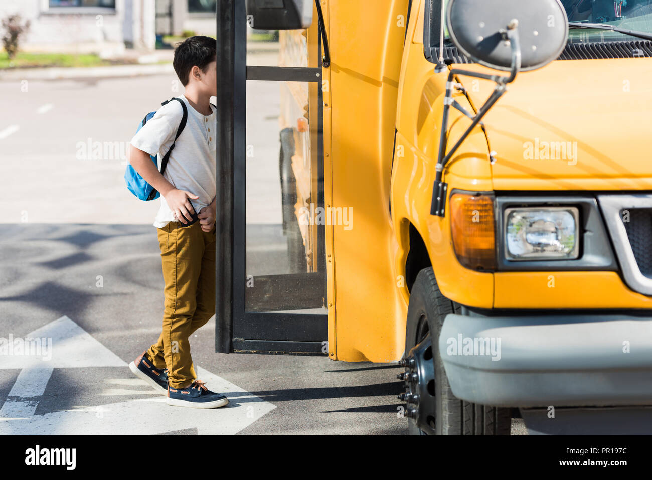 side view of schoolboy entering school bus Stock Photo - Alamy