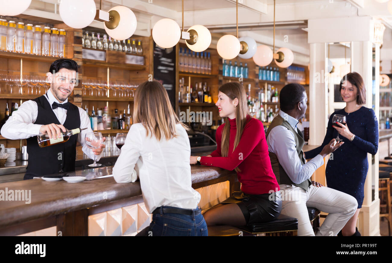 Nice people are relaxing near bar counter and drinking alcohol in ...