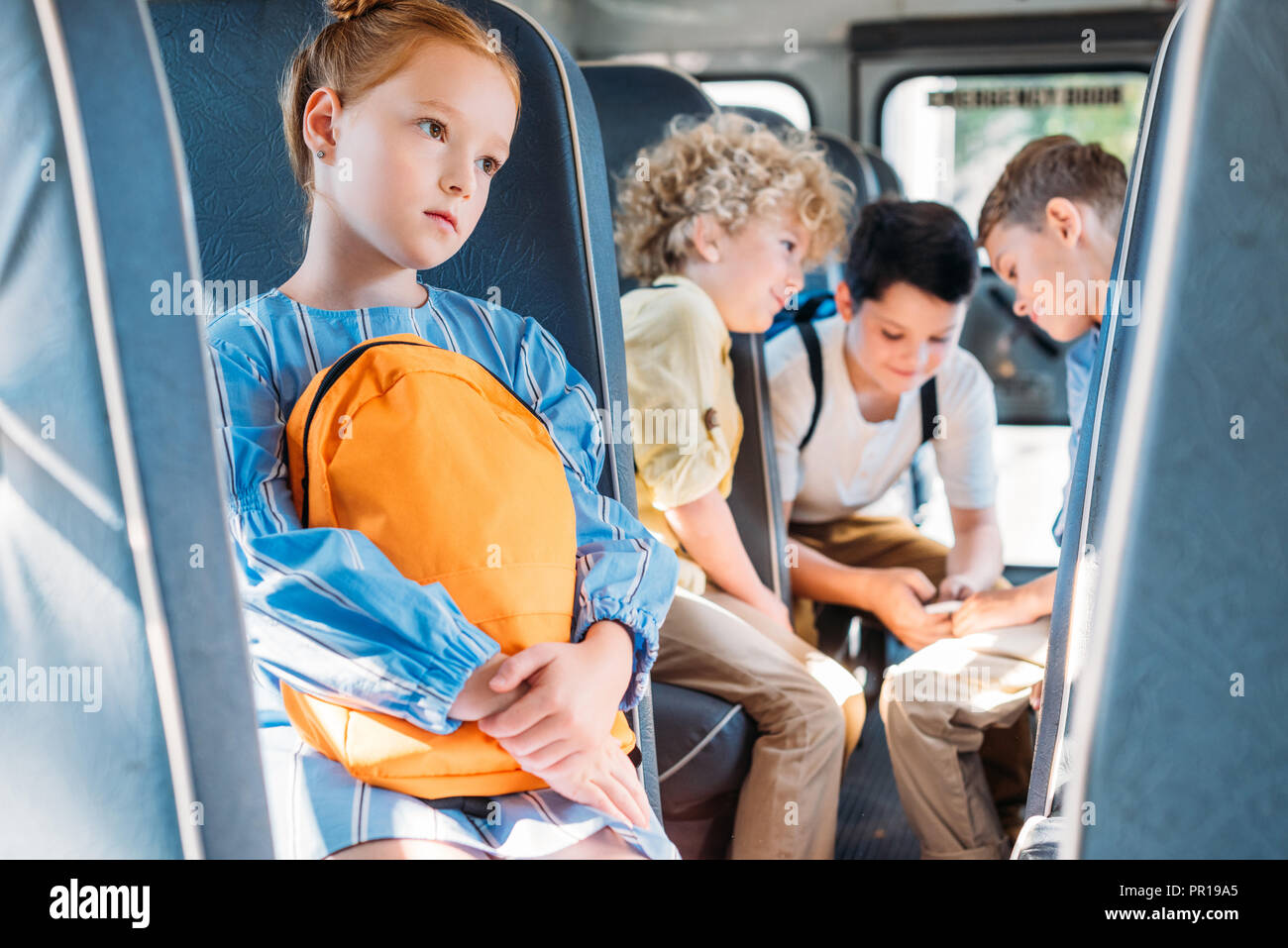 depressed little schoolgirl sitting alone in school bus while her ...