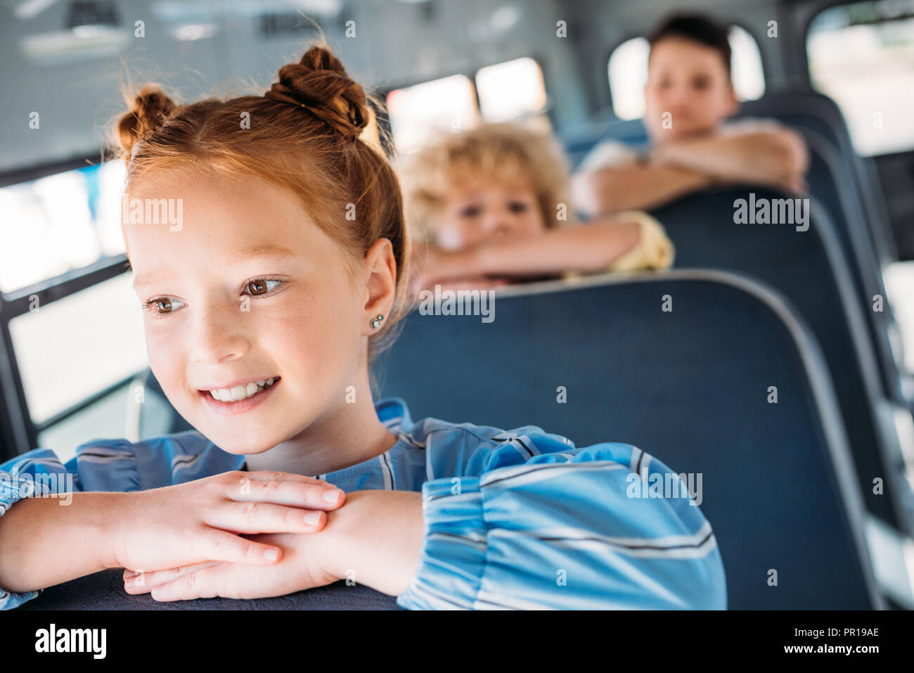 close-up portrait of happy little schoolgirl riding on school bus with ...