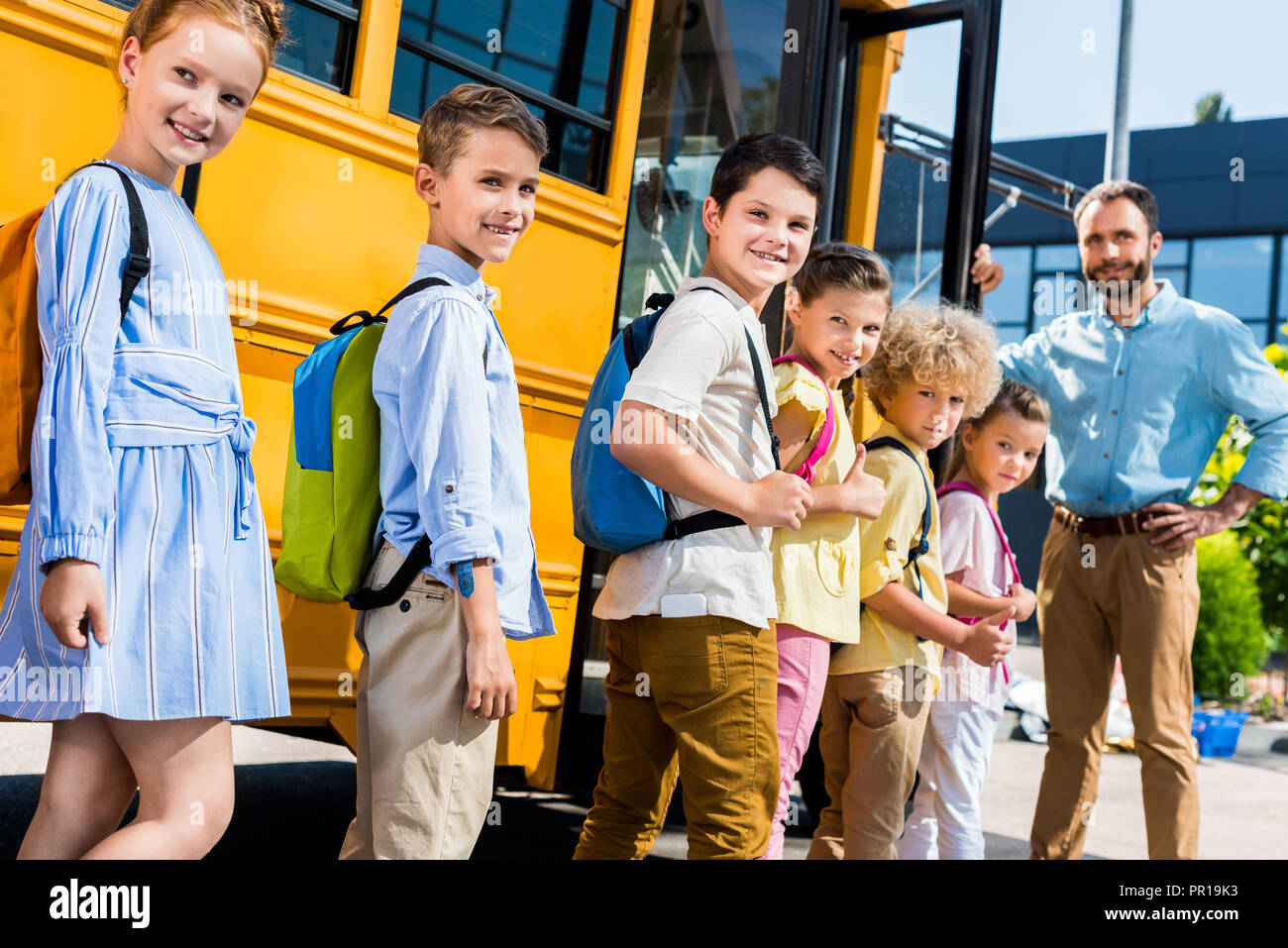 queue of pupils standing near school bus with teacher Stock Photo - Alamy