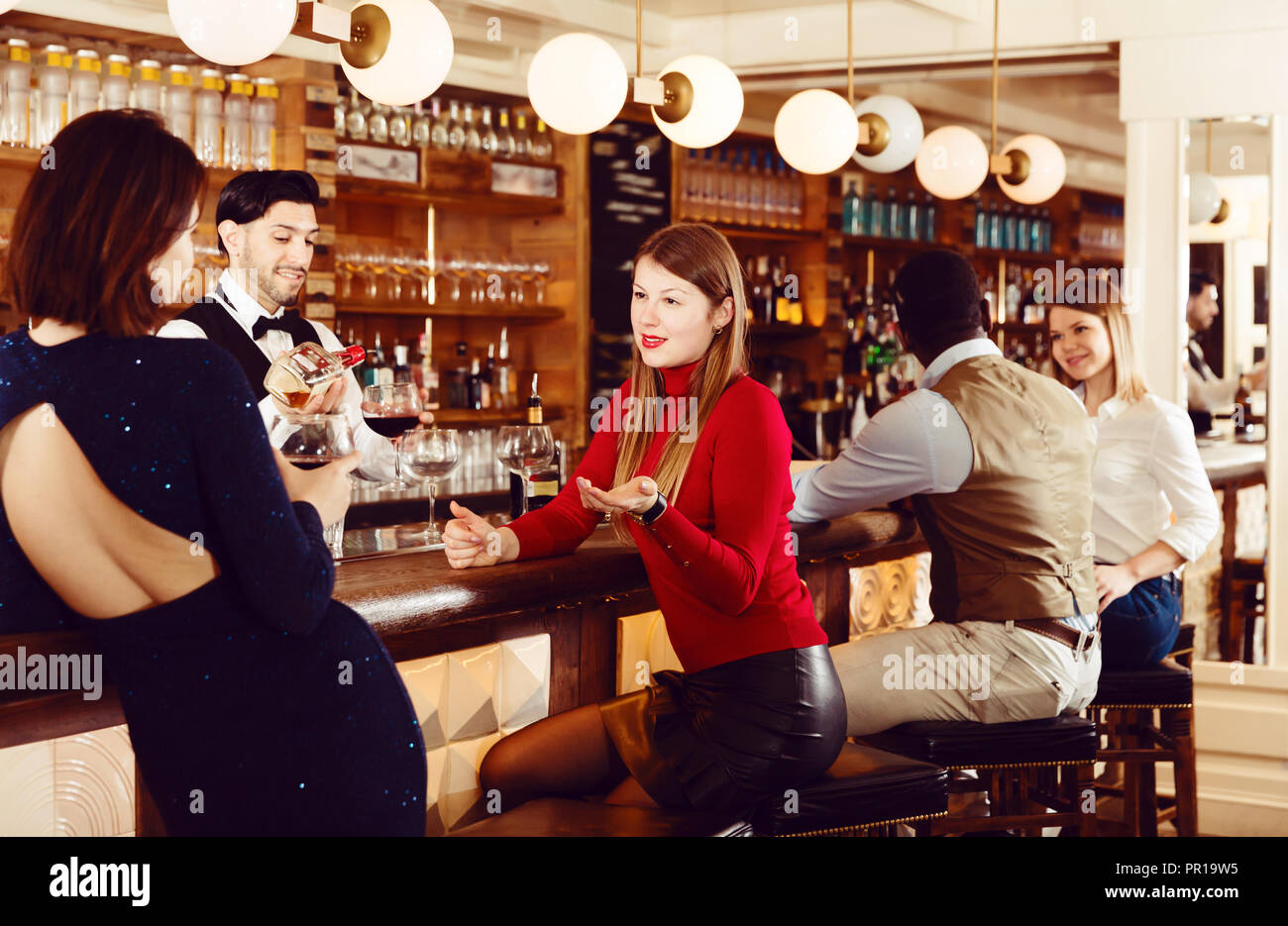 Young people are relaxing near bar counter and drinking alcohol in ...