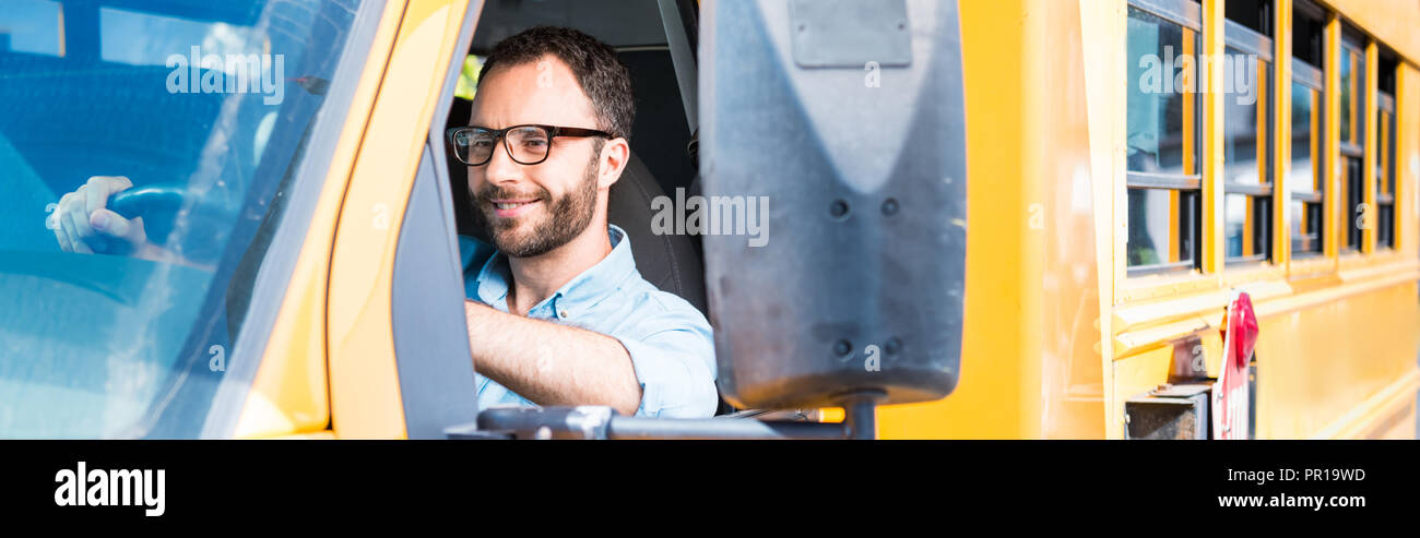 panoramic shot of handsome school bus driver smiling and driving Stock ...