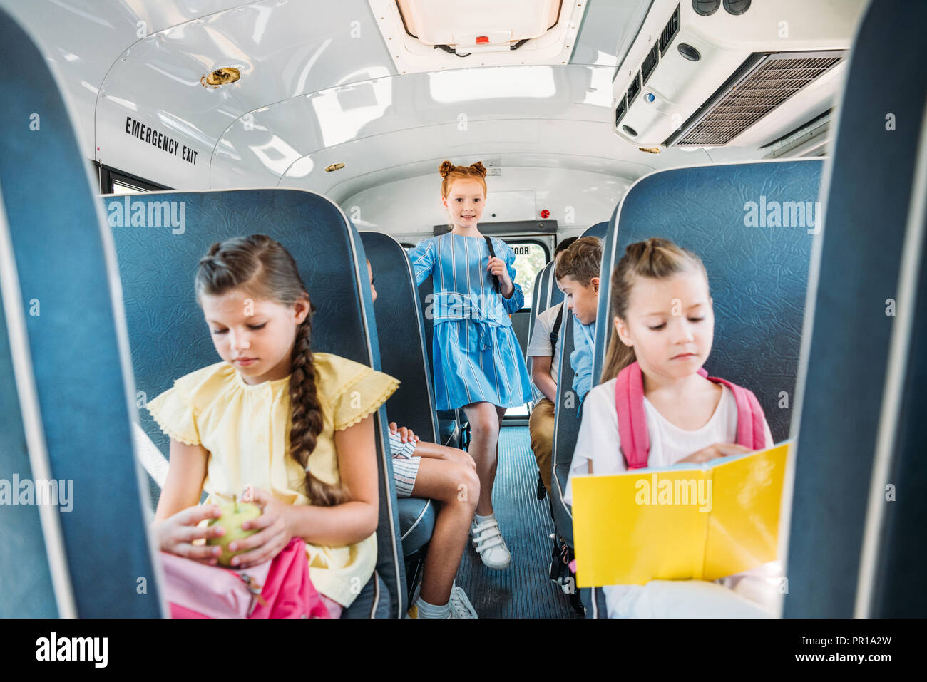 adorable little schoolchildren riding on school bus during excursion ...