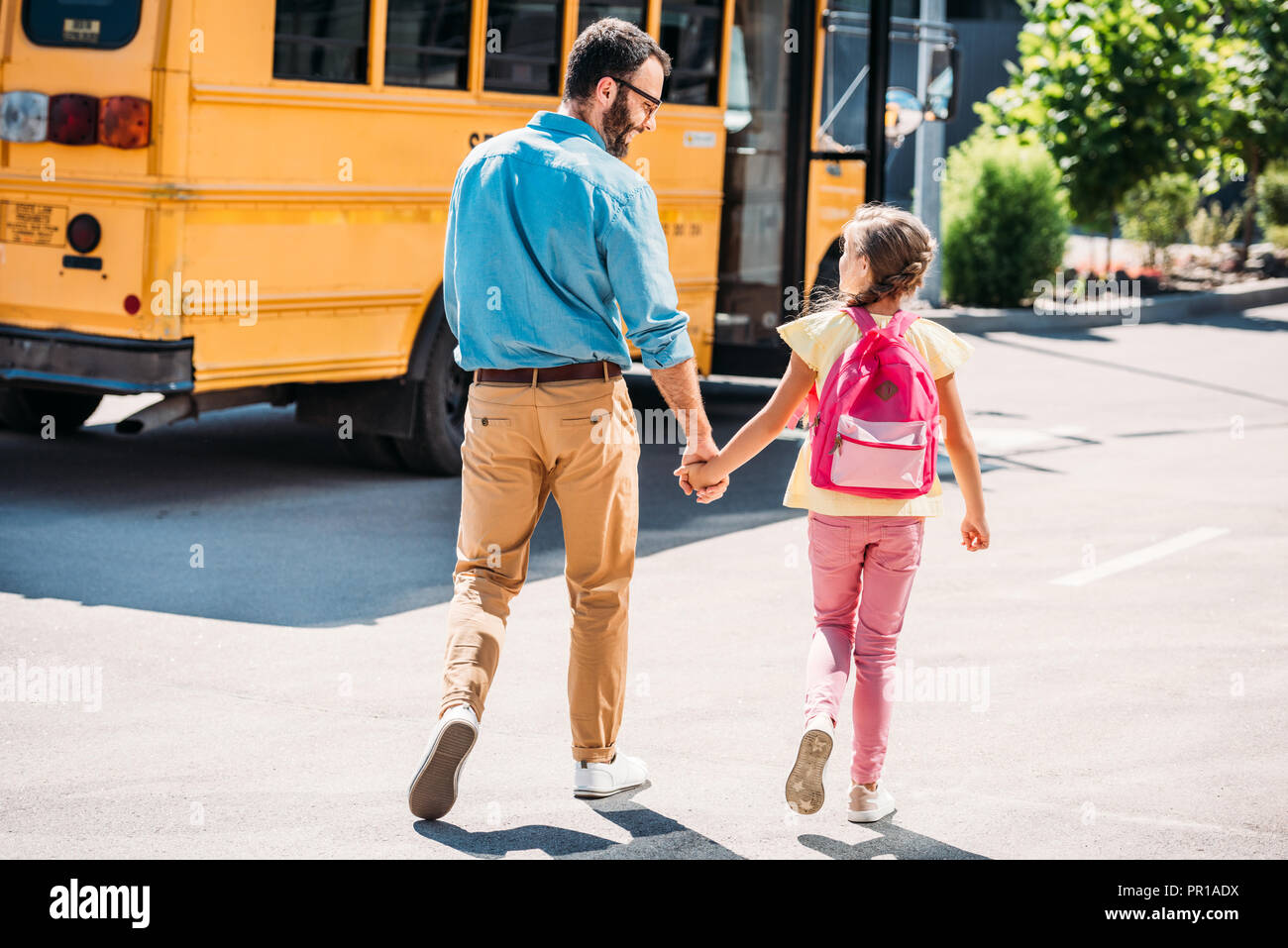 Back View Of Father And Daughter Holding Hands And Walking To School