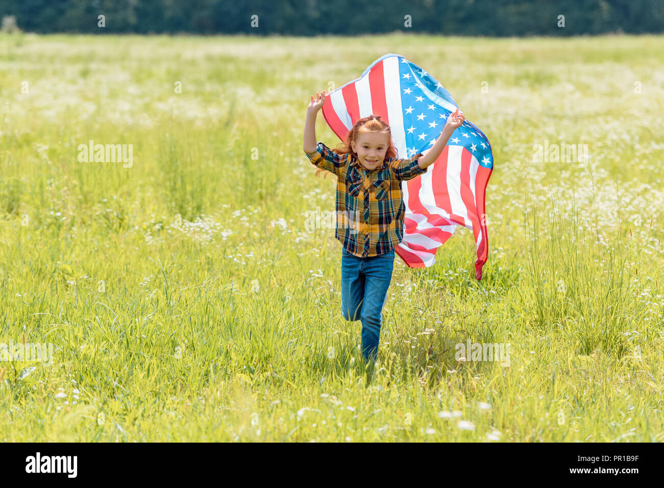 cheerful child running in field with american flag in hands Stock Photo ...