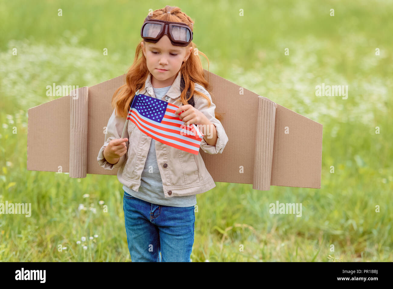 portrait of kid in pilot costume with american flagpole standing in ...