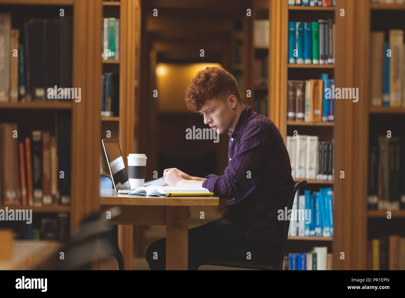 College student reading a book in library Stock Photo - Alamy