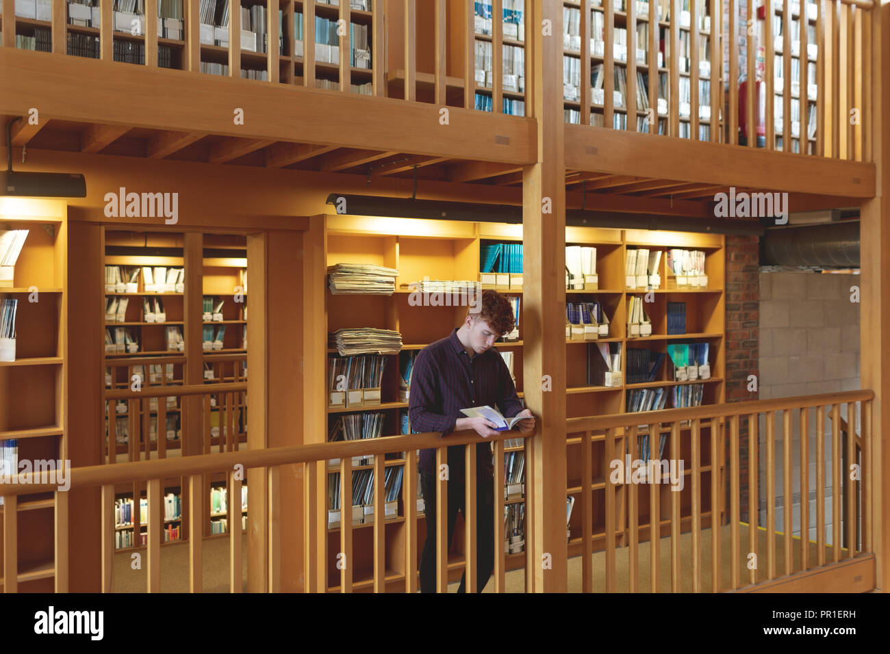 College student reading a book in library Stock Photo - Alamy
