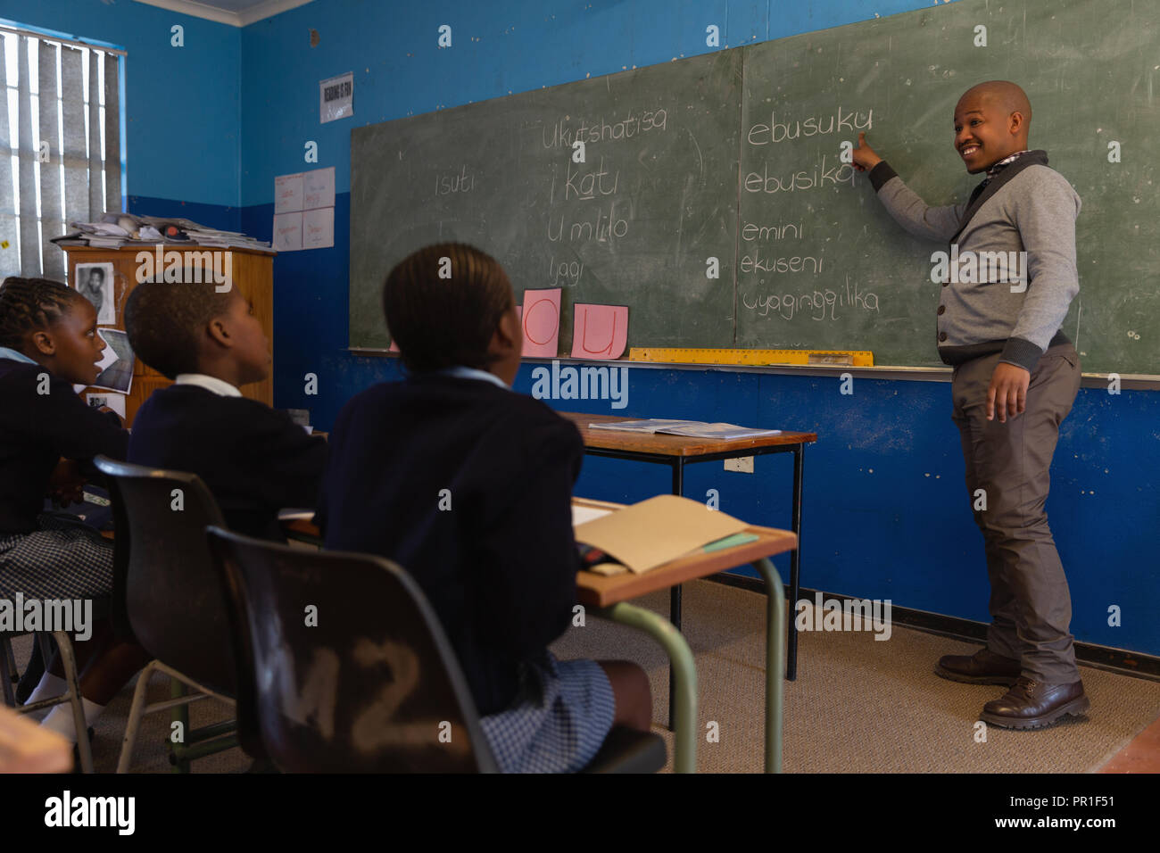 Male teacher teaching students in the class Stock Photo - Alamy