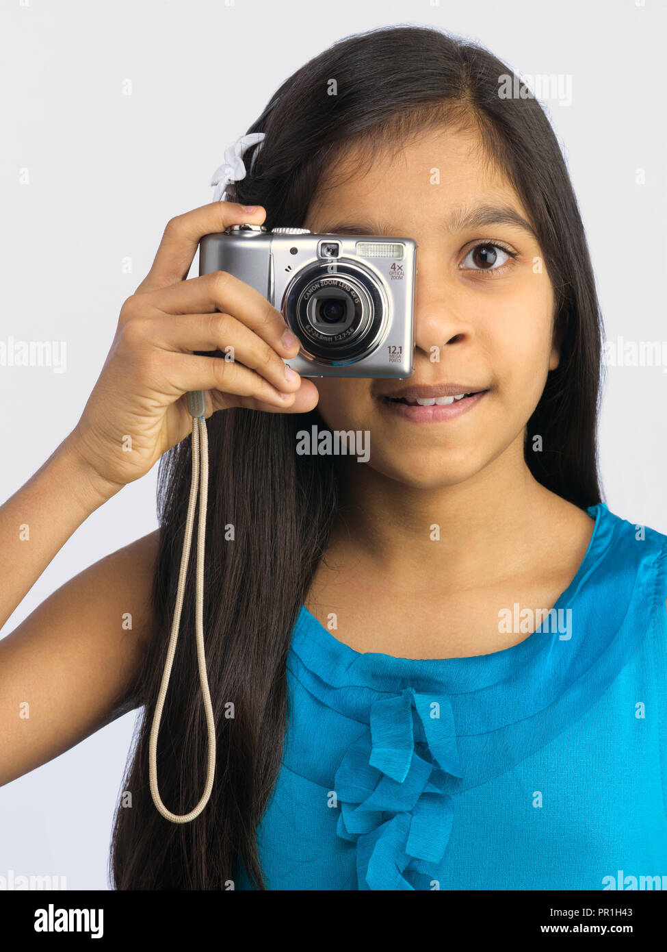 YOUNG INDIAN GIRL TAKING A PHOTOGRAPH WITH A CAMERA. SHOT AGAINST A ...