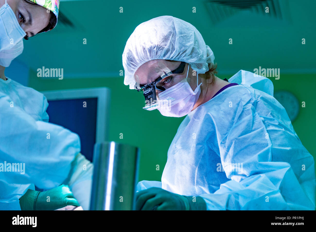 Surgeon and his assistant performing cosmetic surgery on nose in ...