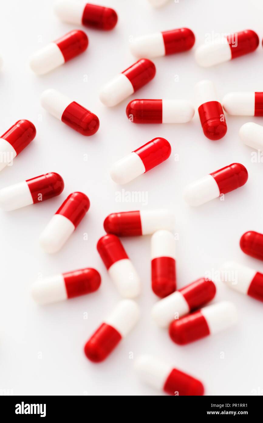 Red and white drug capsules scattered on a white background Stock Photo ...