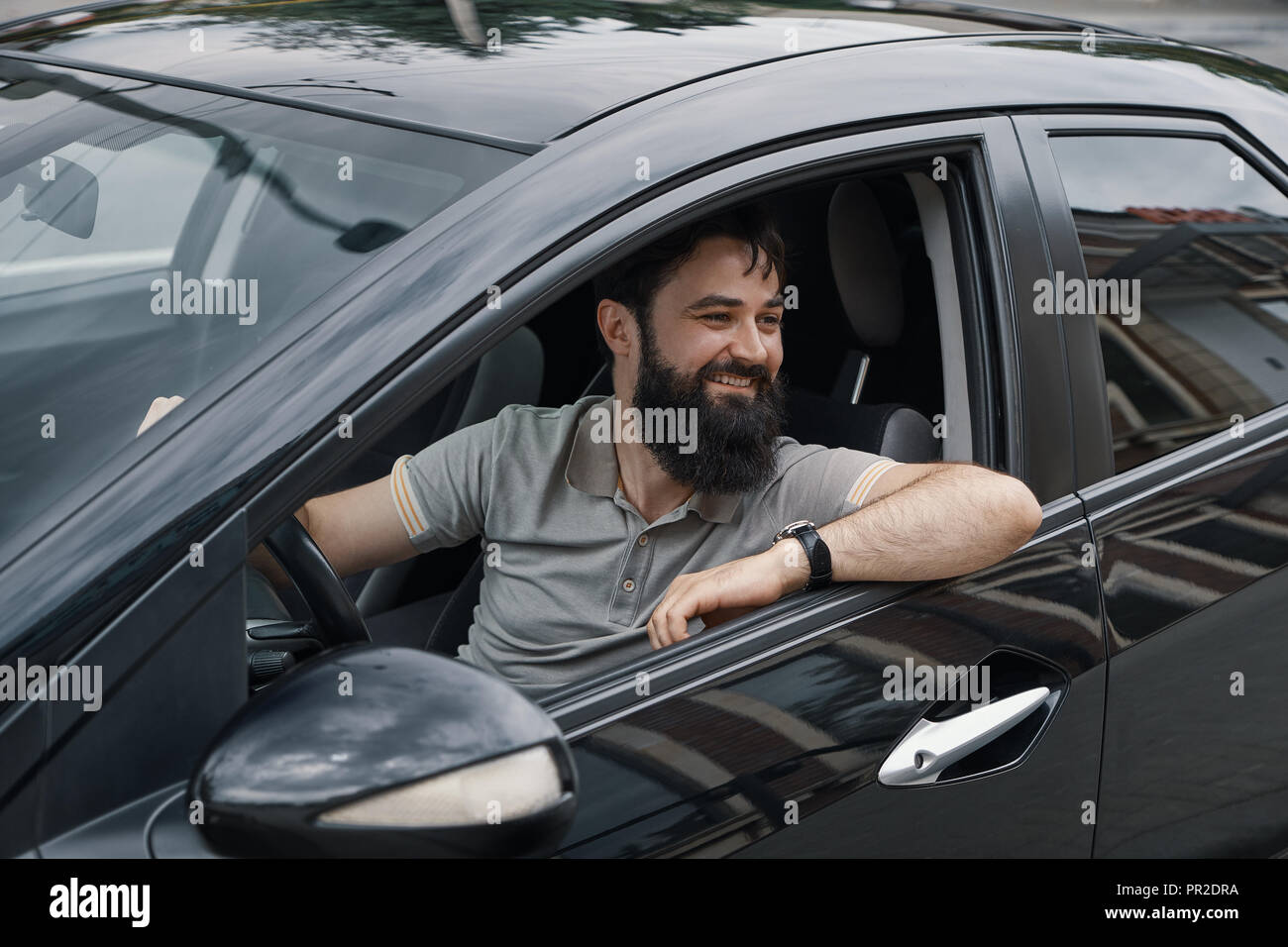 Handsome young man smiling while driving a car. Happy male driver ...