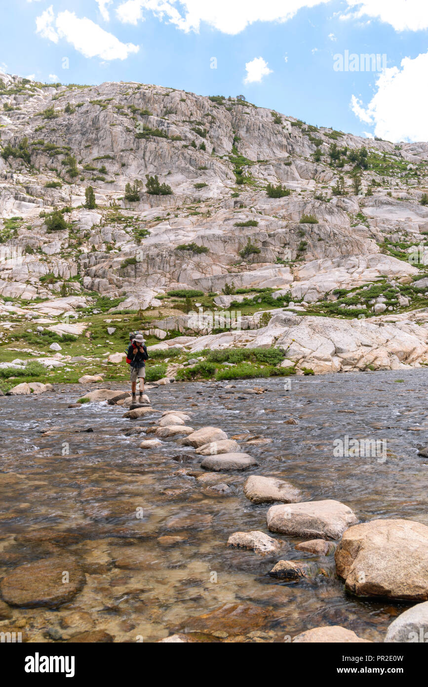 A teenage backpacker crosses Evolution Lake Inlet. John Muir Trail ...