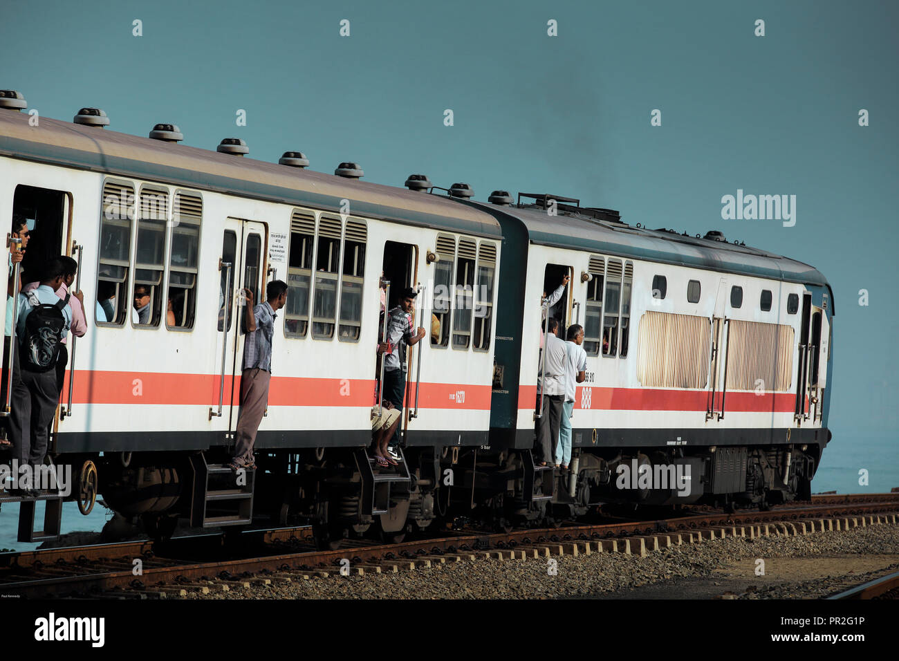 Men hanging out doors of crowded commuter train near Colombo, Sri Lanka ...