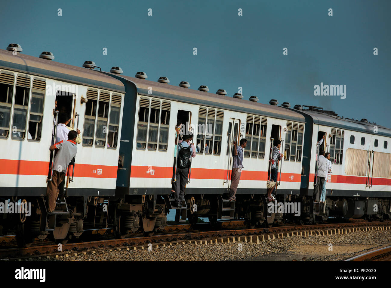 Men hanging out doors of crowded commuter train near Colombo, Sri Lanka ...