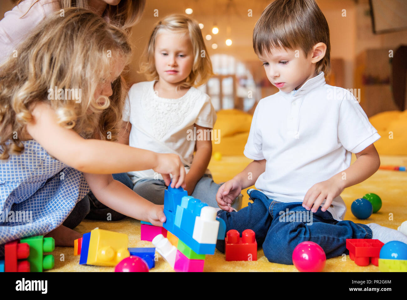 adorable kids playing with constructor on floor in kindergarten Stock ...
