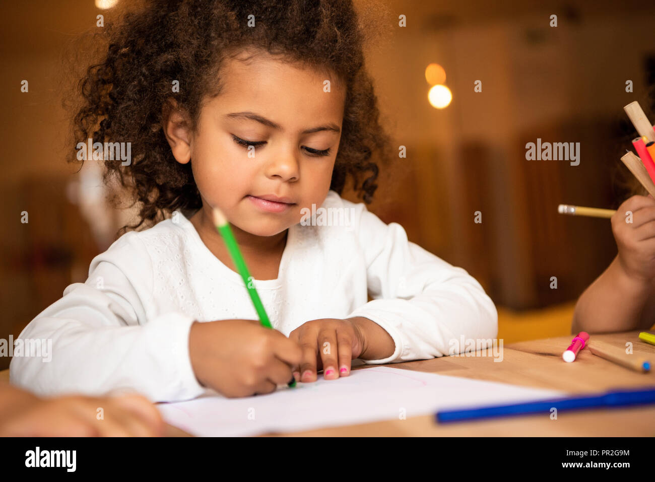 adorable african american kid erasing pencil from sheet of paper in ...