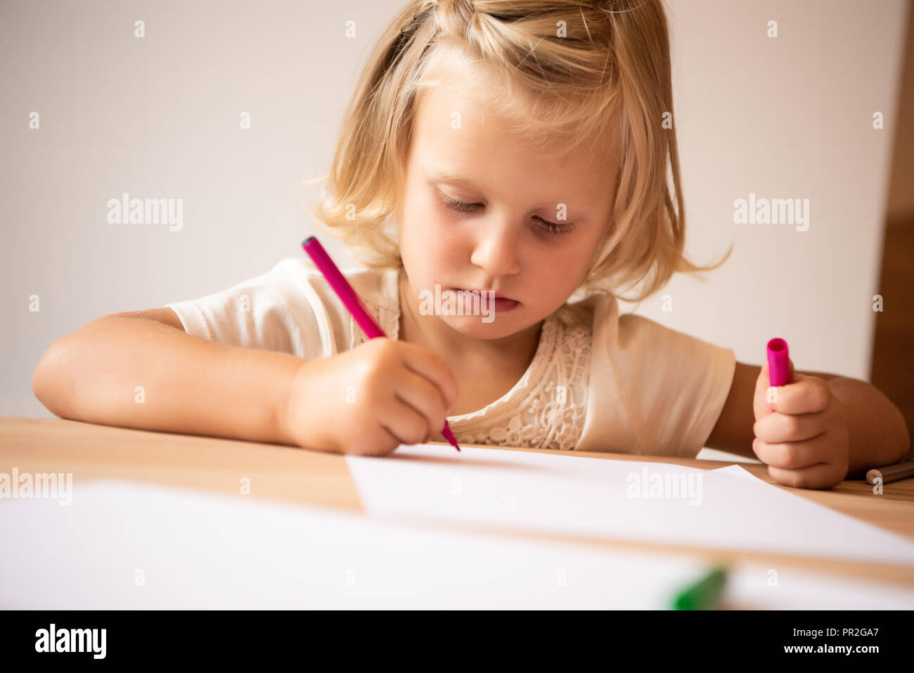 serious adorable kid drawing with pink felt pen in kindergarten Stock ...