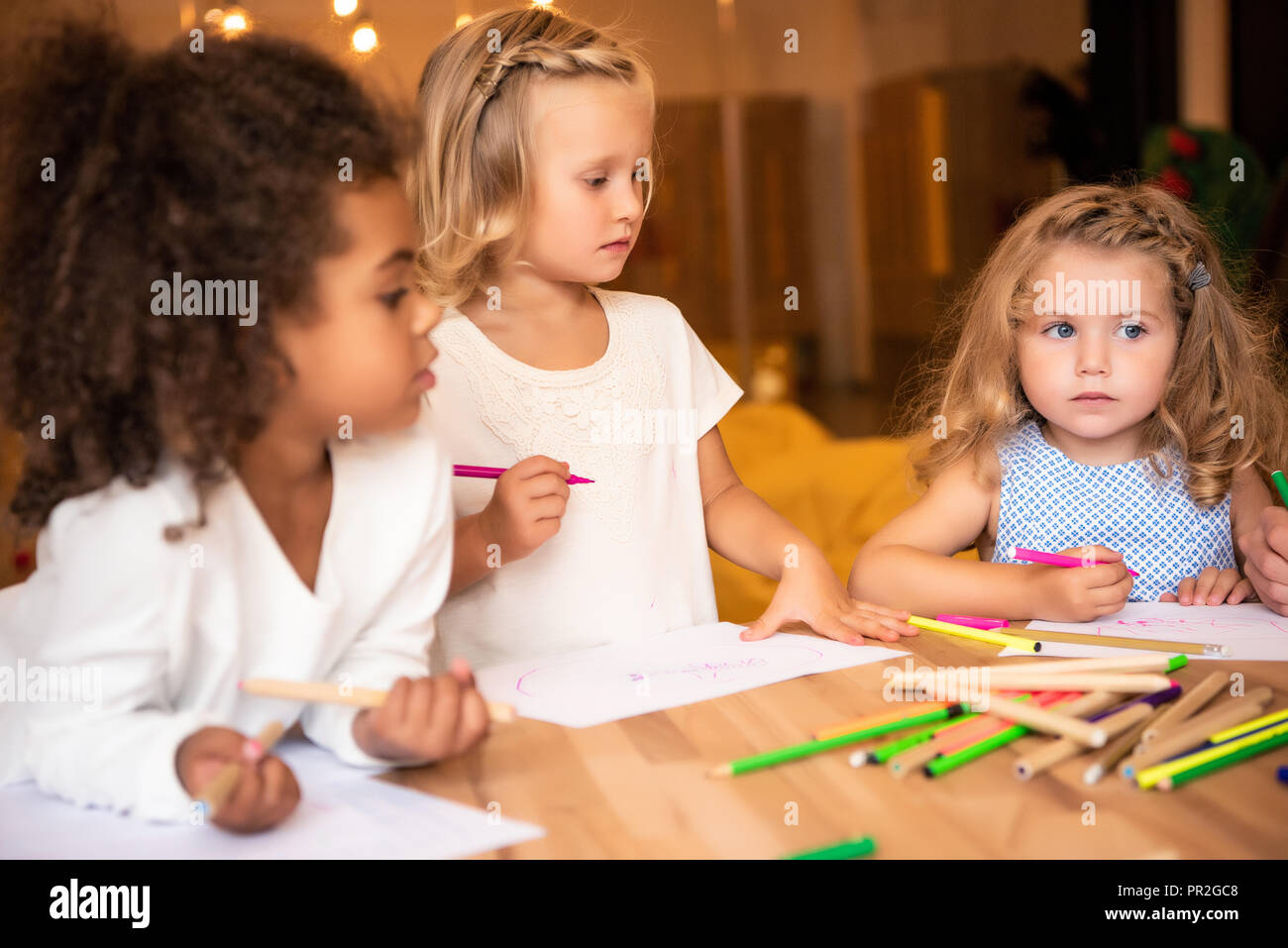 multiethnic kids drawing together with felt tip pens in kindergarten ...
